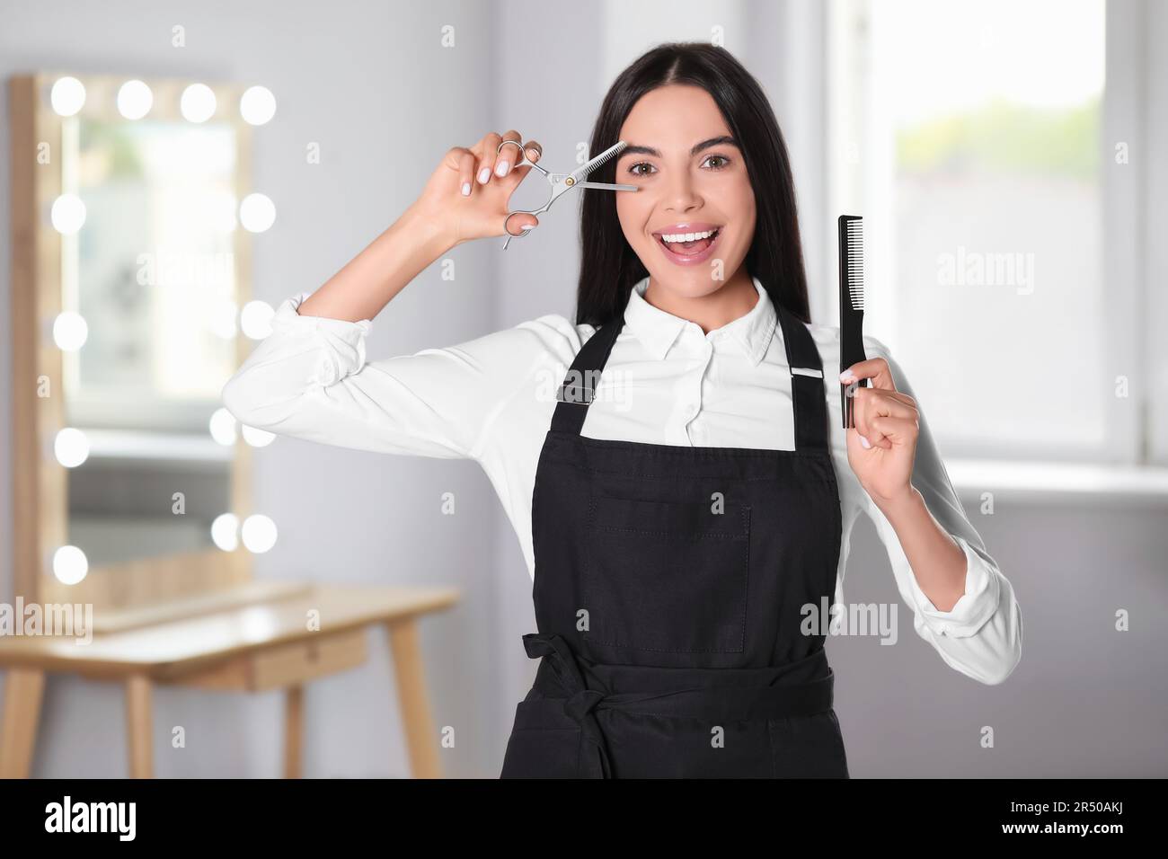 Portrait of happy hairdresser with professional tools in beauty salon ...