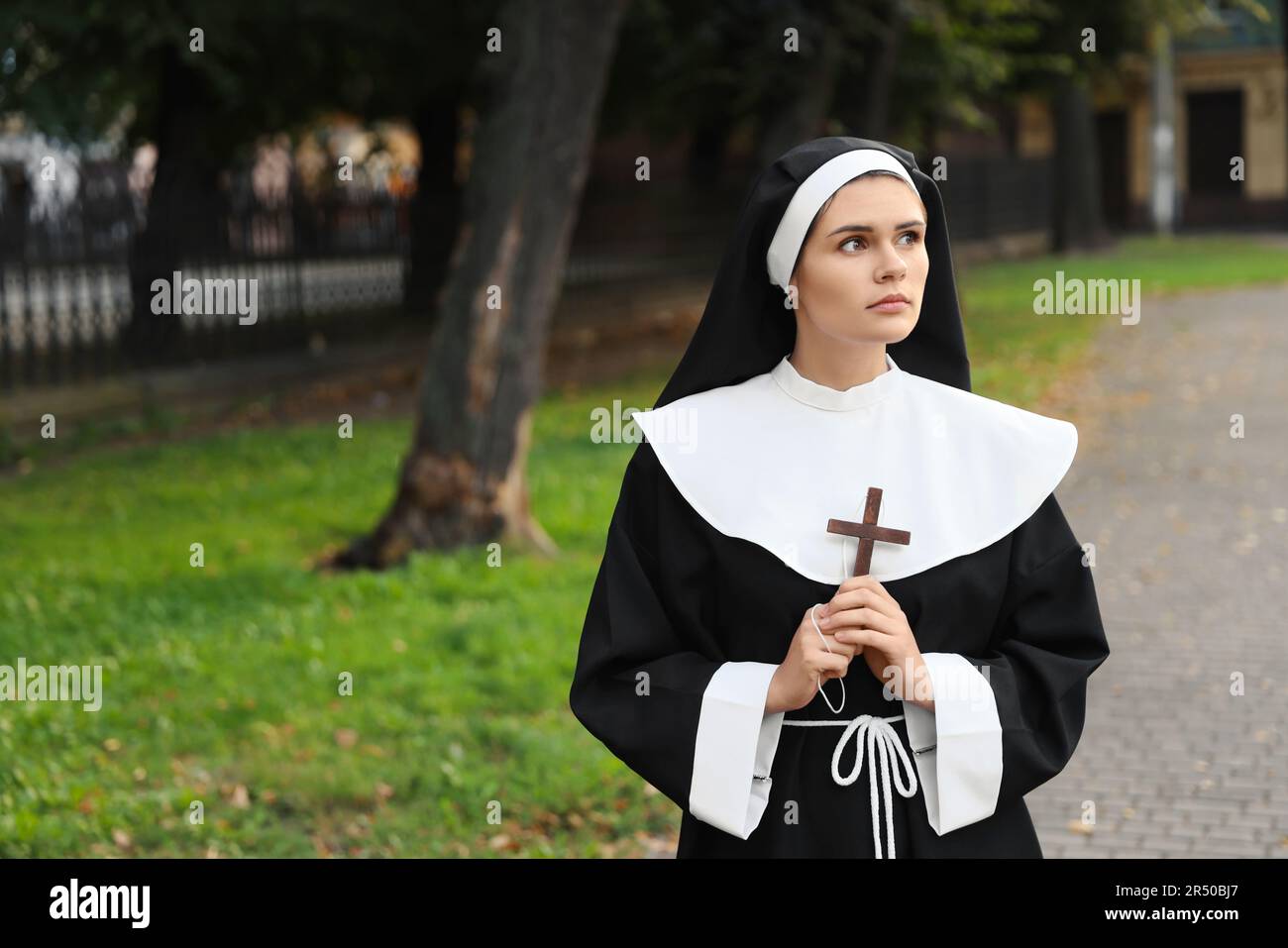 Young nun with Christian cross in park outdoors, space for text Stock ...