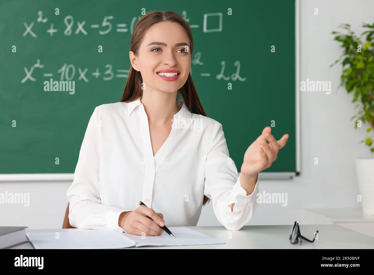 Young math’s teacher giving lesson at table in classroom Stock Photo ...