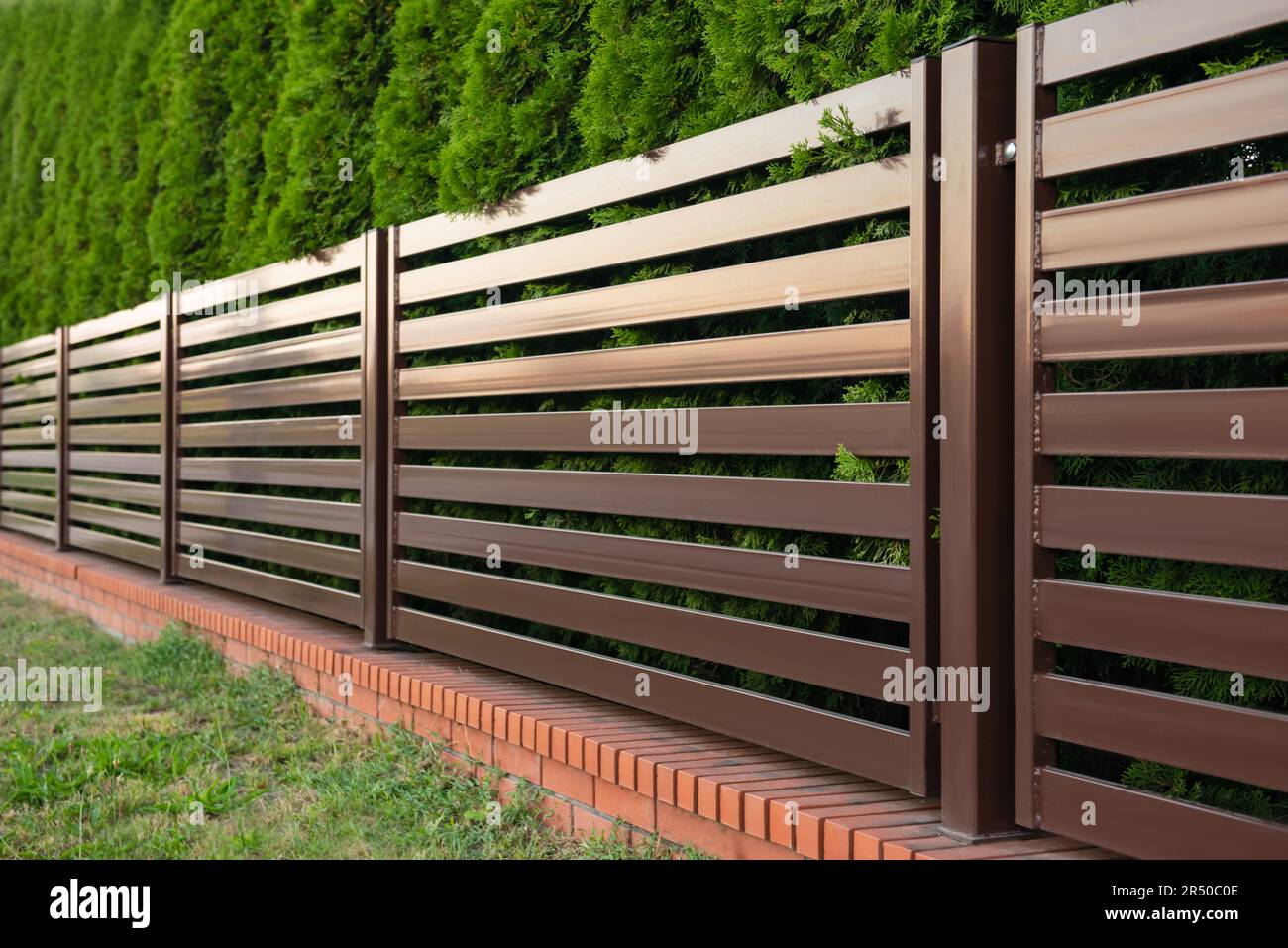 Beautiful fence with brick and brown iron railing Stock Photo - Alamy