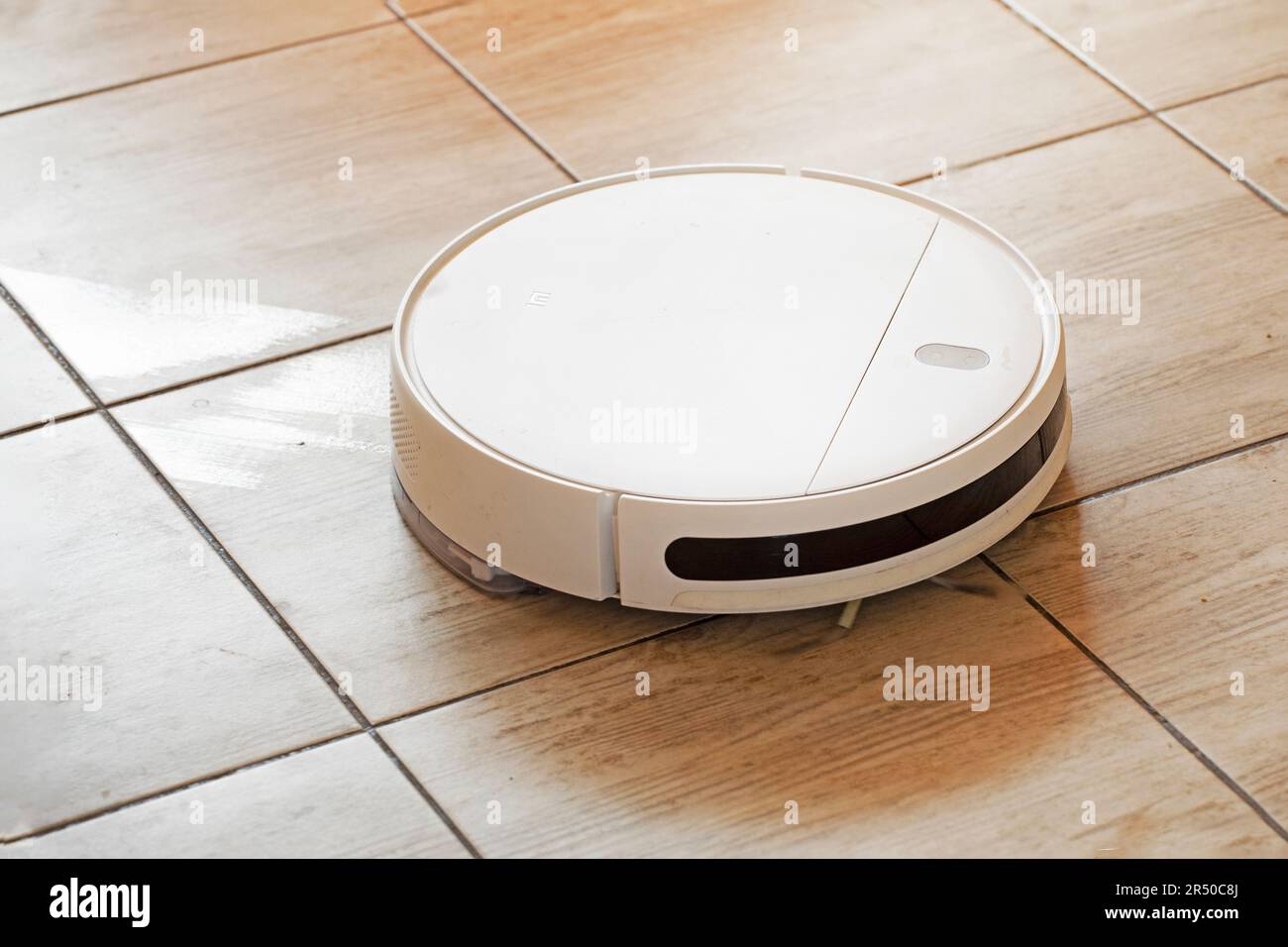 robot vacuum cleaner cleans and washes the floors on the tiled floor in ...
