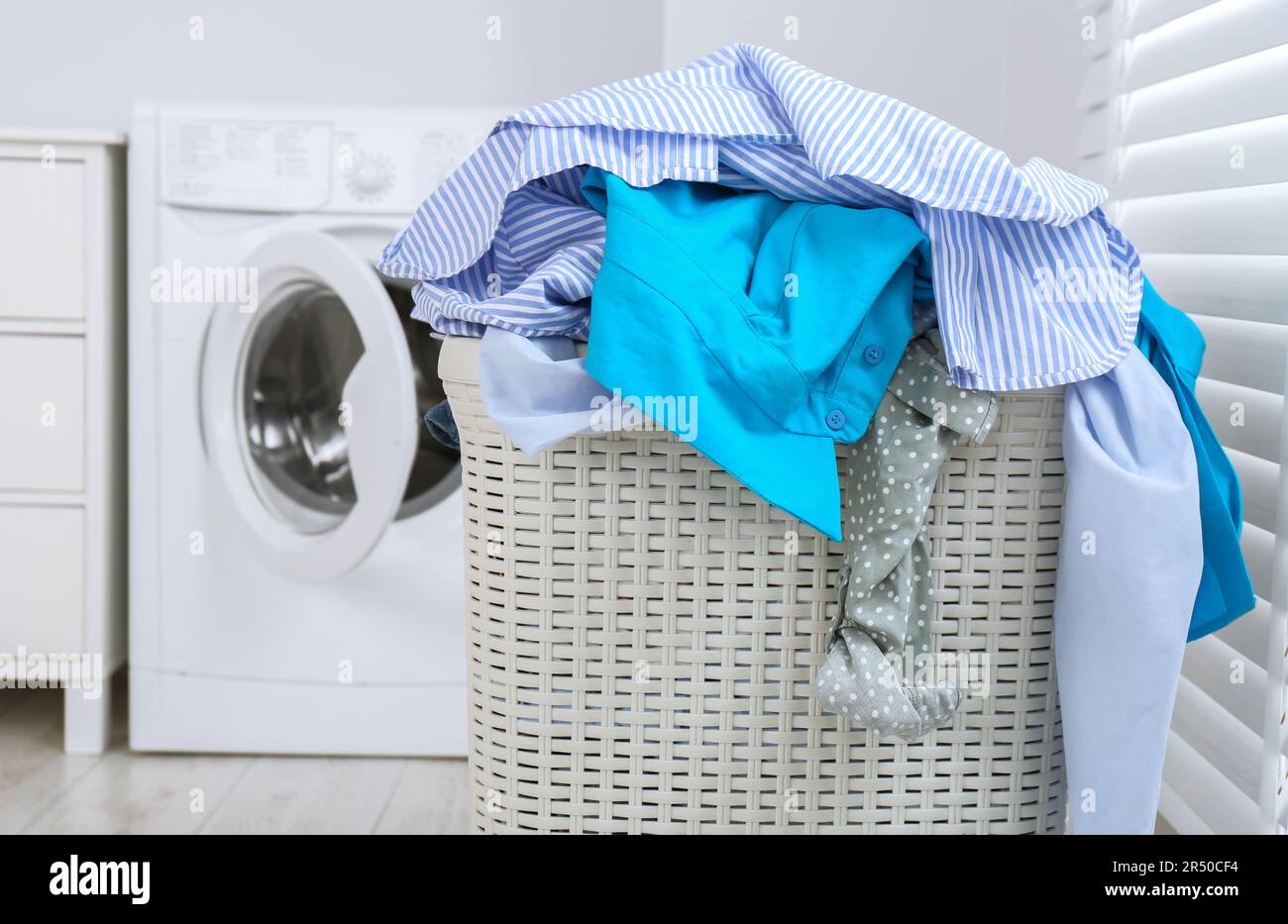 Plastic laundry basket overfilled with clothes in bathroom, closeup ...