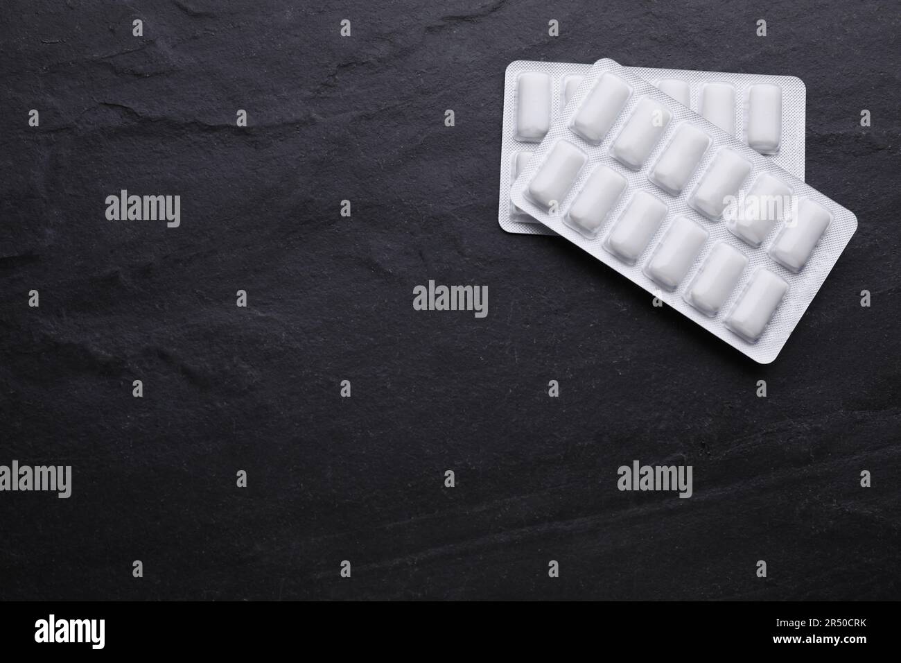 Blisters with chewing gums on black table, top view. Space for text ...