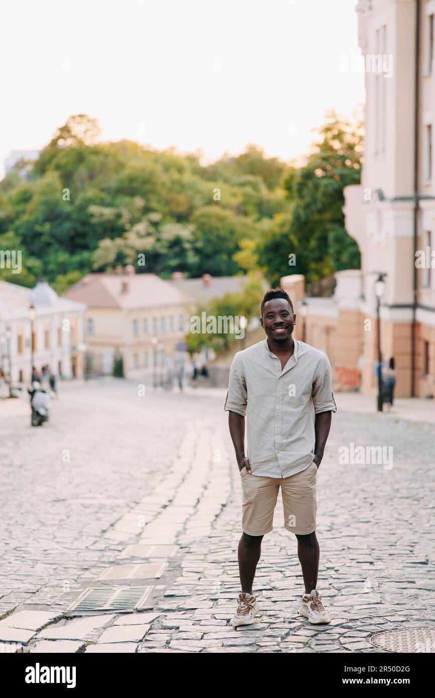 Young smiling african man is standing among street during walk in city ...