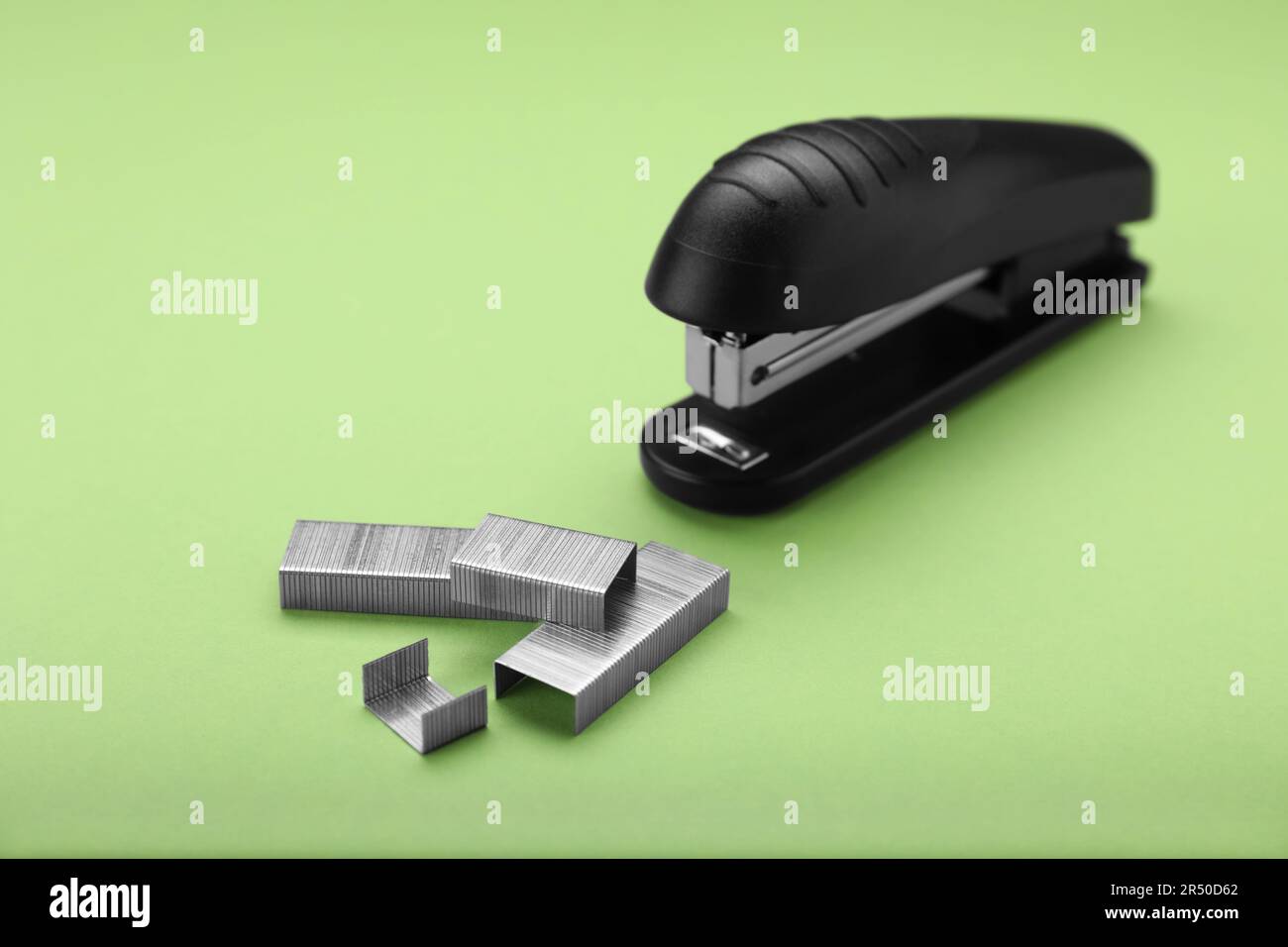 New bright stapler with staples on green background. School stationery ...