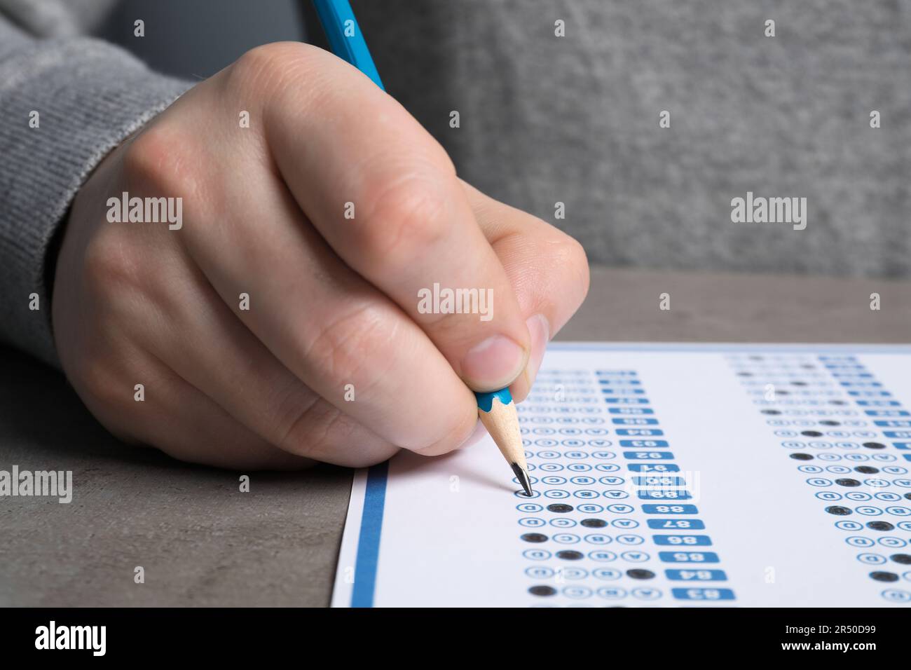 Student filling answer sheet at grey table, closeup. Passing exam Stock ...