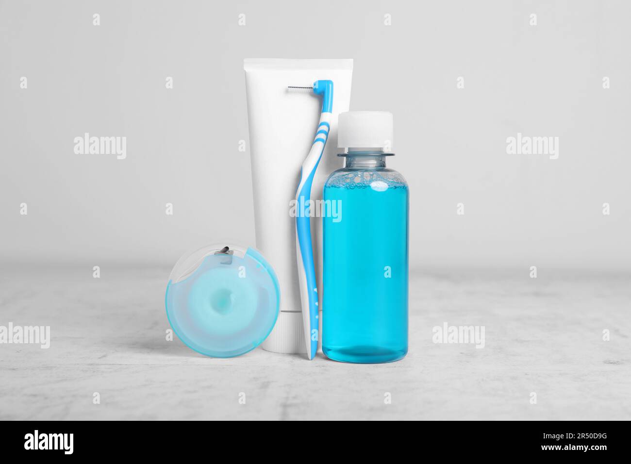 Dental floss and different teeth care products on light grey textured ...