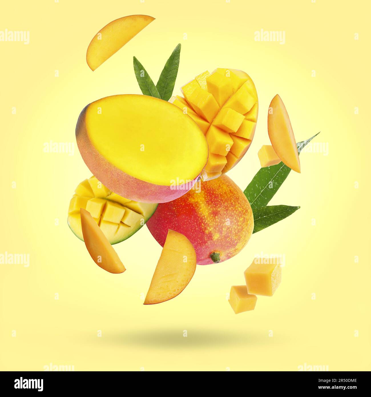 Delicious mango fruits and leaves falling on pale yellow background ...