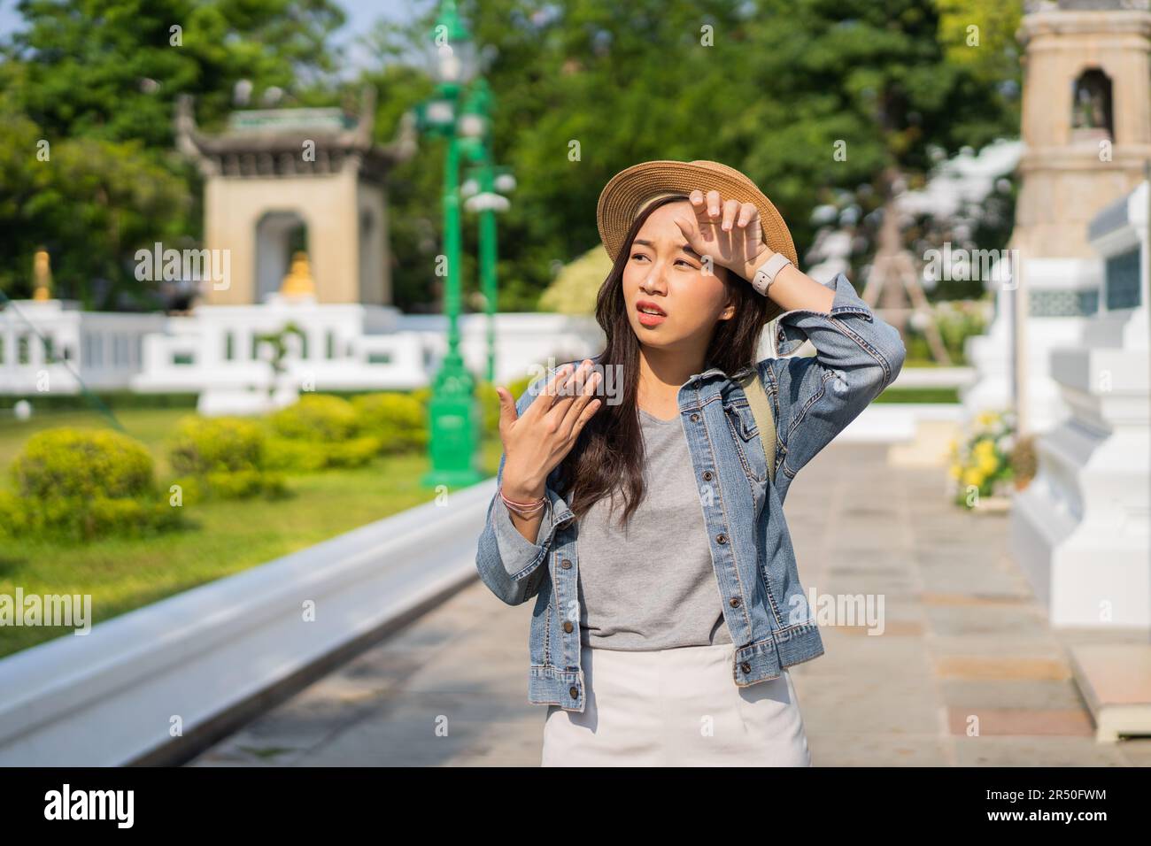Portrait of Asian female traveler fanning and sweating on sidewalk of ...