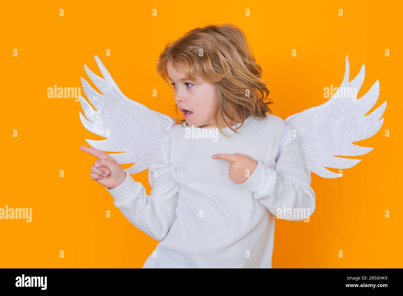Child angel pointing finger, point gesture. Kid wearing angel costume ...