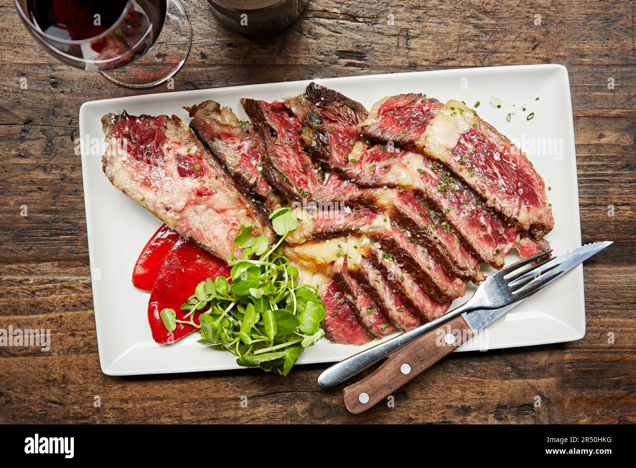 Rare slices of steak served with a glass of red wine Stock Photo - Alamy