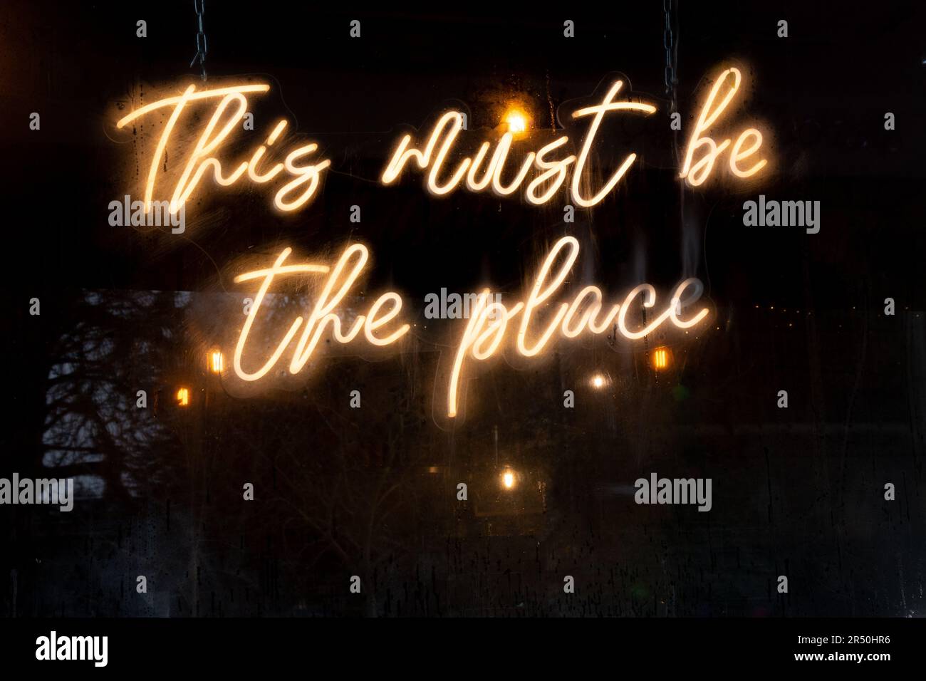 A neon sign inside a cafe window reads This Must Be The Place ...