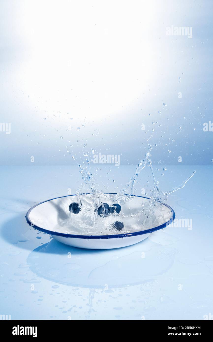 Blueberries falling splashing into plates with water Stock Photo - Alamy