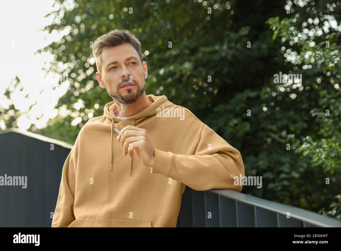 Man smoking cigarette near railing outdoors. Bad habit Stock Photo - Alamy