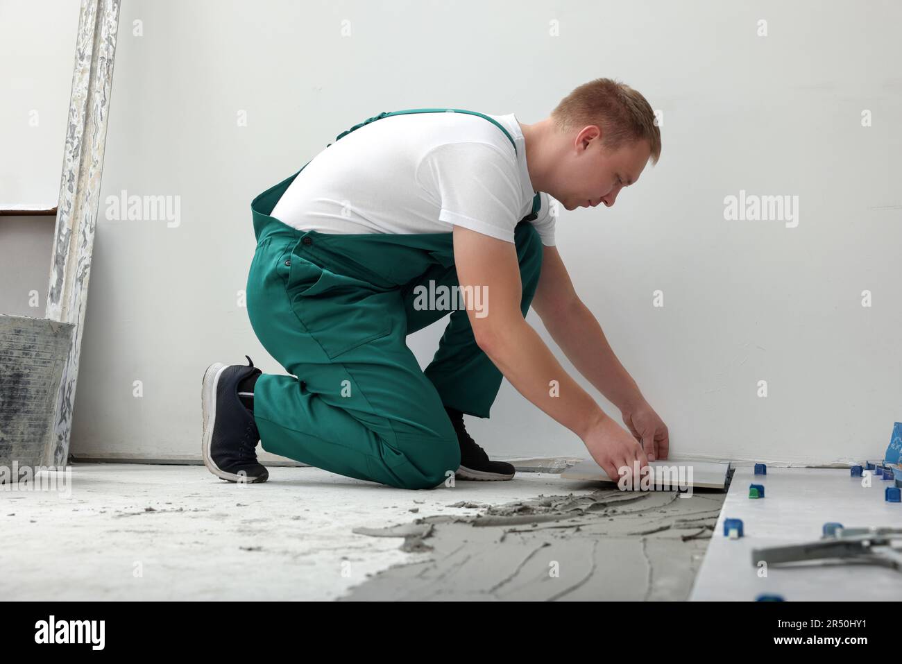 Worker installing ceramic tile on floor near wall Stock Photo - Alamy