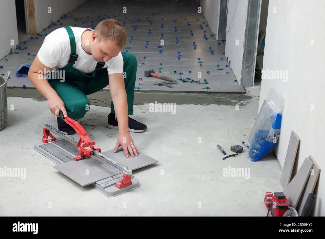 Worker using manual tile cutter in room Stock Photo - Alamy