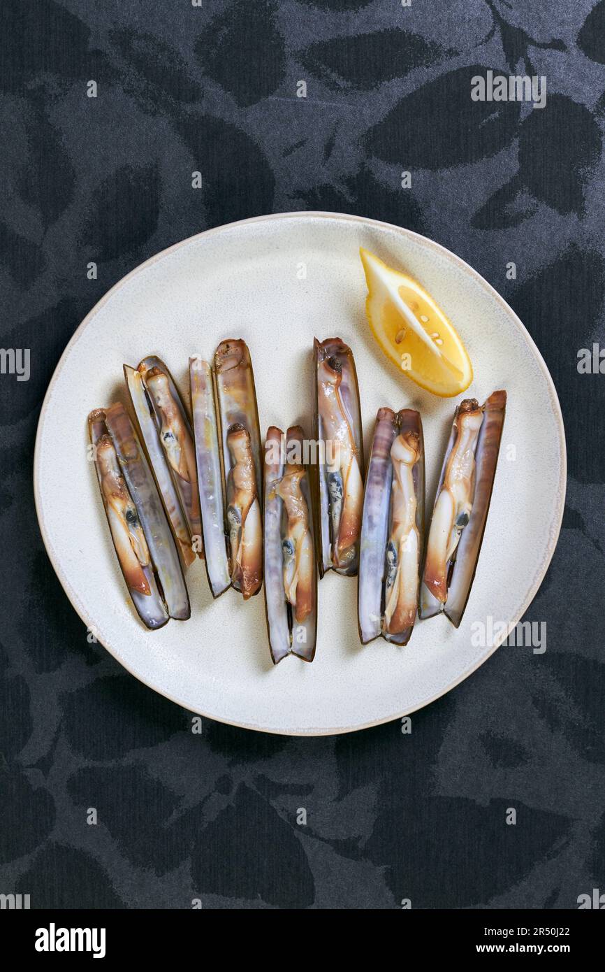 Grilled razor clams with lemon slice on white plate Stock Photo - Alamy
