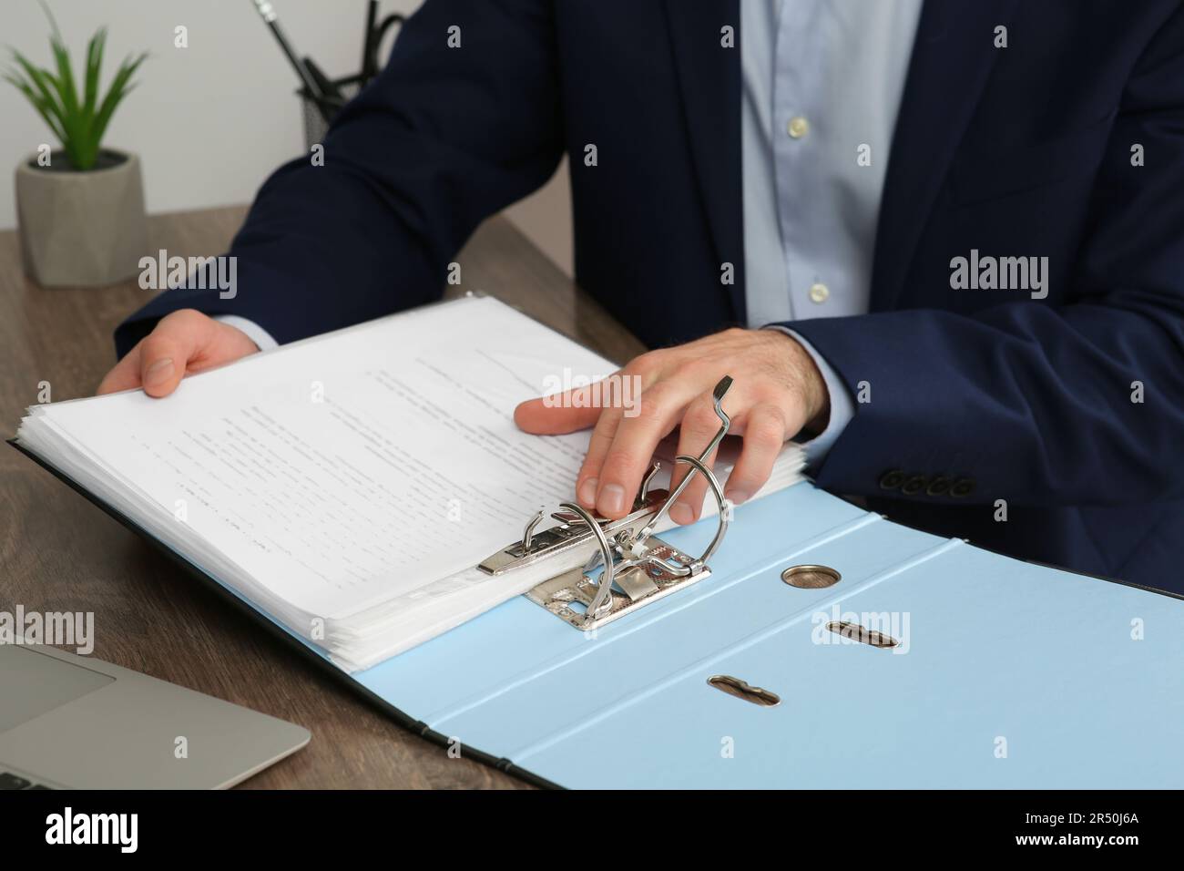 Businessman putting document into file folder at wooden table in office ...