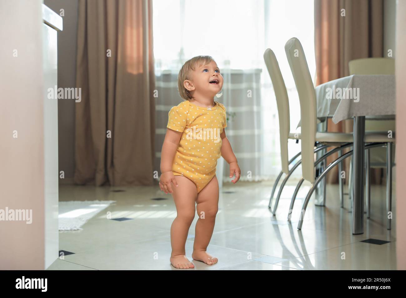 Cute baby learning to walk in room Stock Photo - Alamy