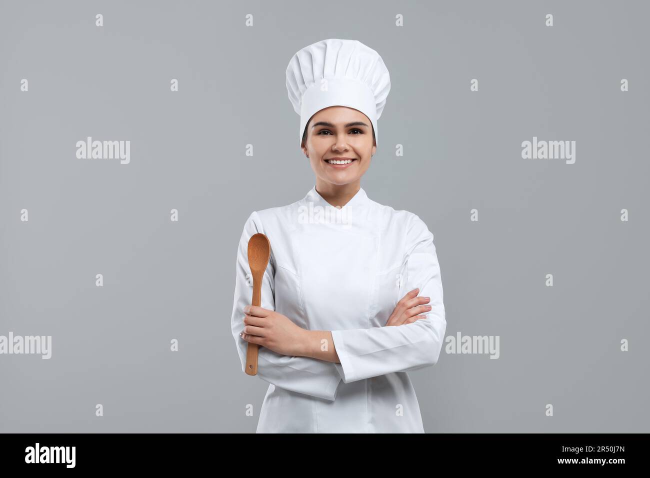 Happy female chef with wooden spoon on light grey background Stock ...