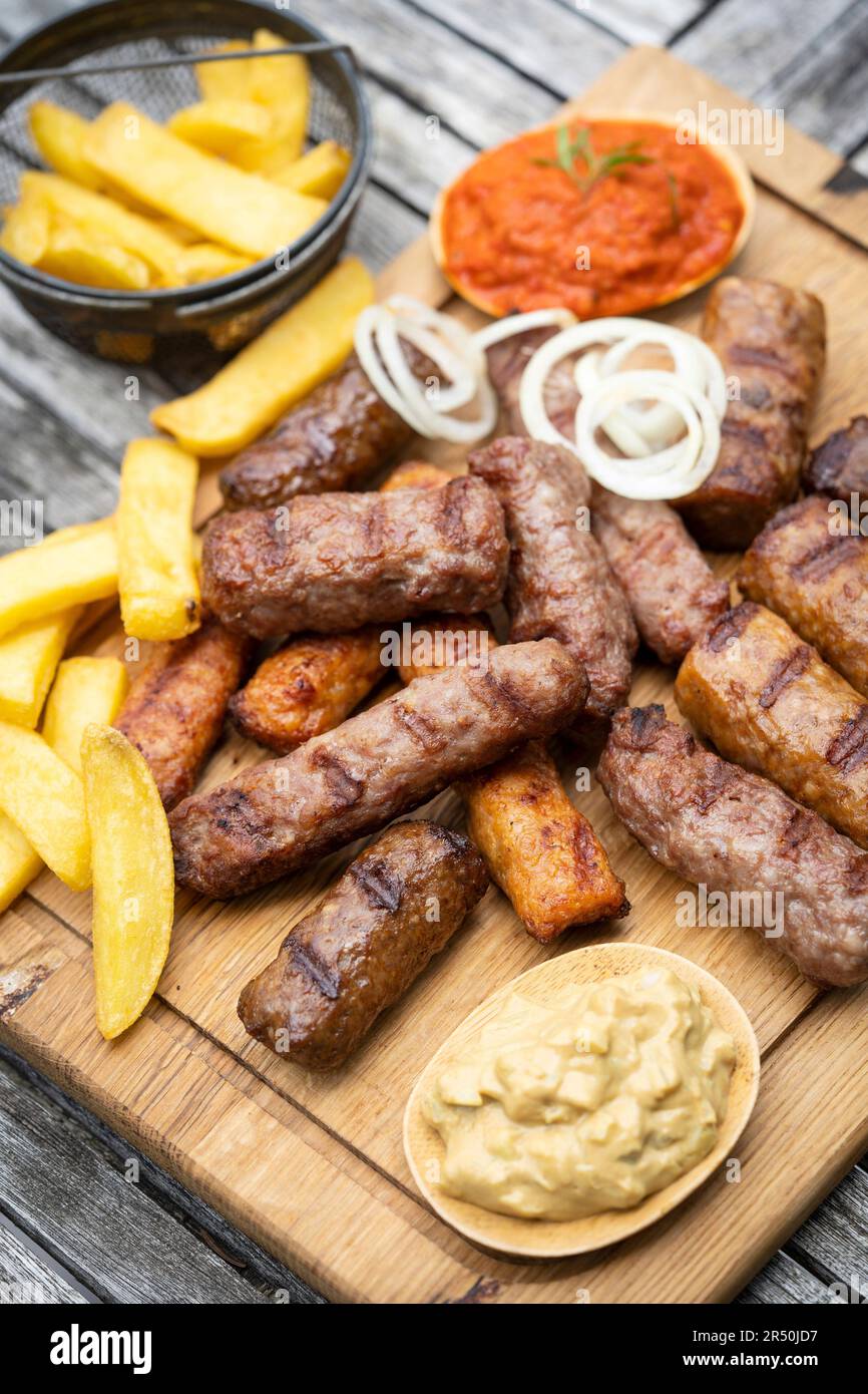 Grilled cevapcici with onion mustard, ajvar, onions and French fries ...