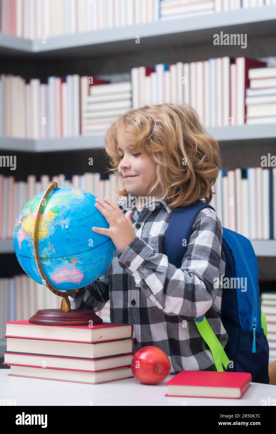 Pupil looking at globe in library at the elementary school. Nerd school ...