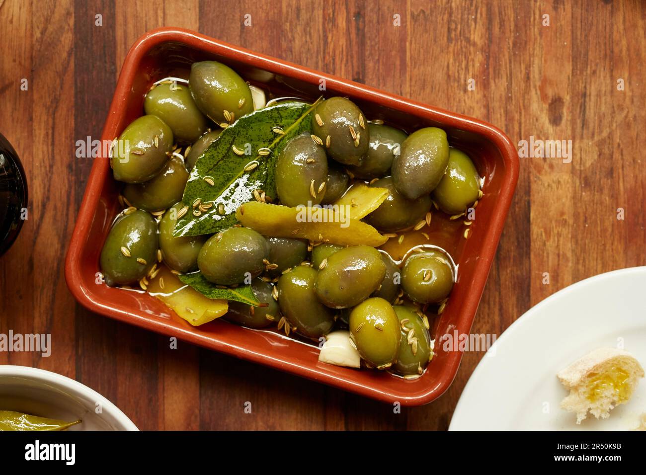 Green olives in oil with lemon and cumin seeds Stock Photo - Alamy
