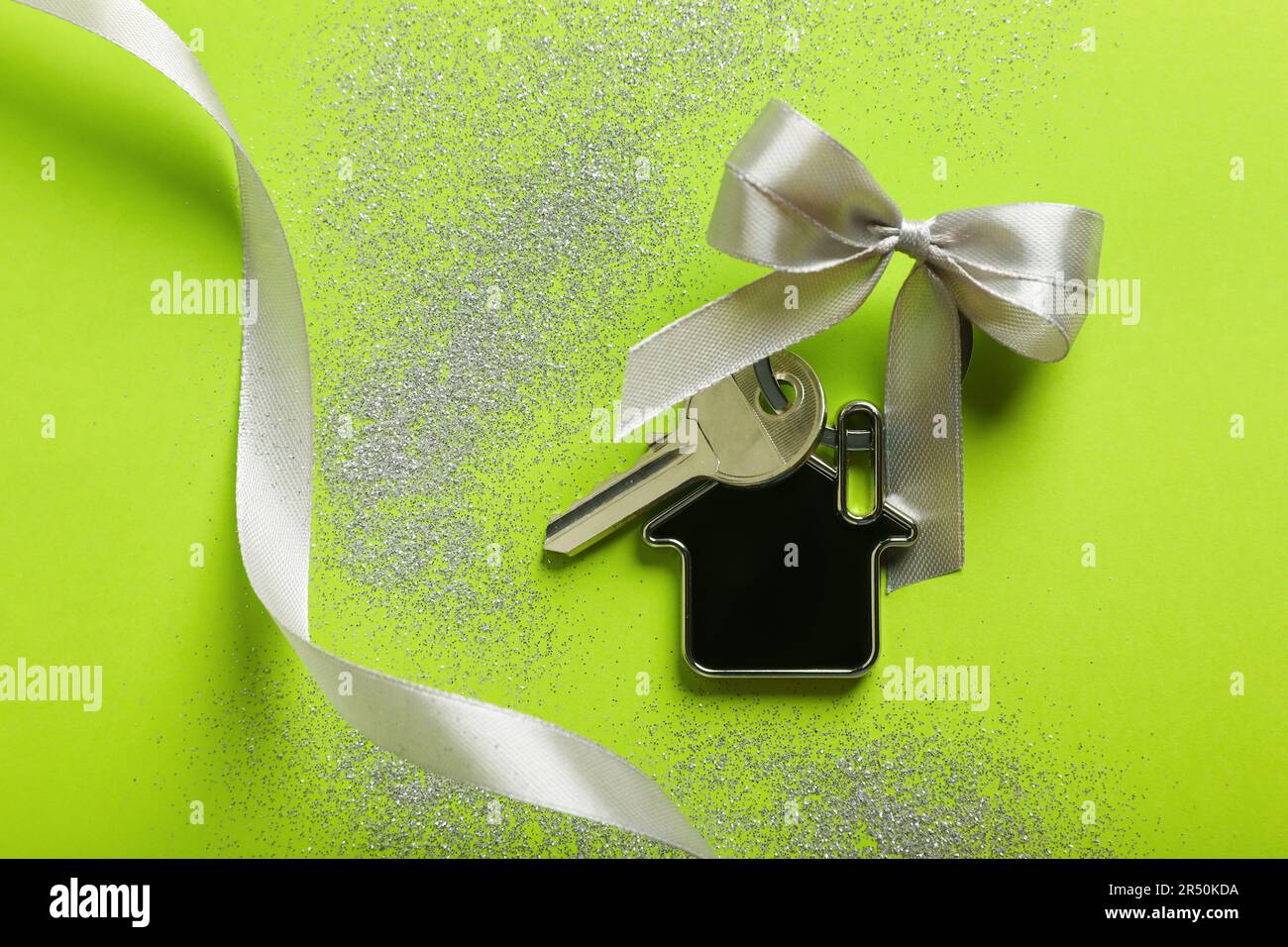 Key with trinket in shape of house, bow, ribbon and glitter on light ...