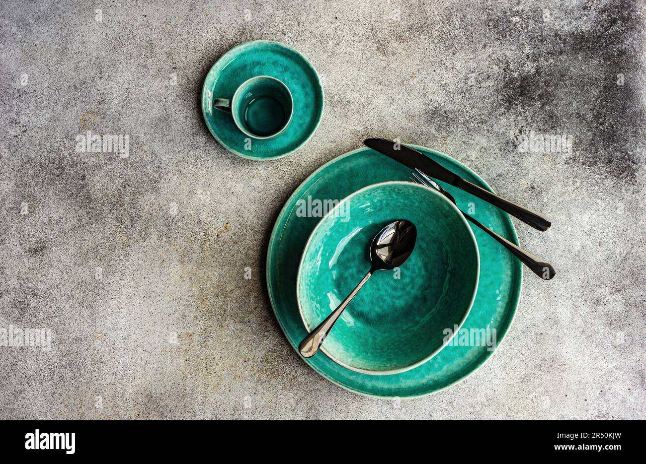 Green earthenware dishes with cutlery on a concrete surface Stock Photo - Alamy