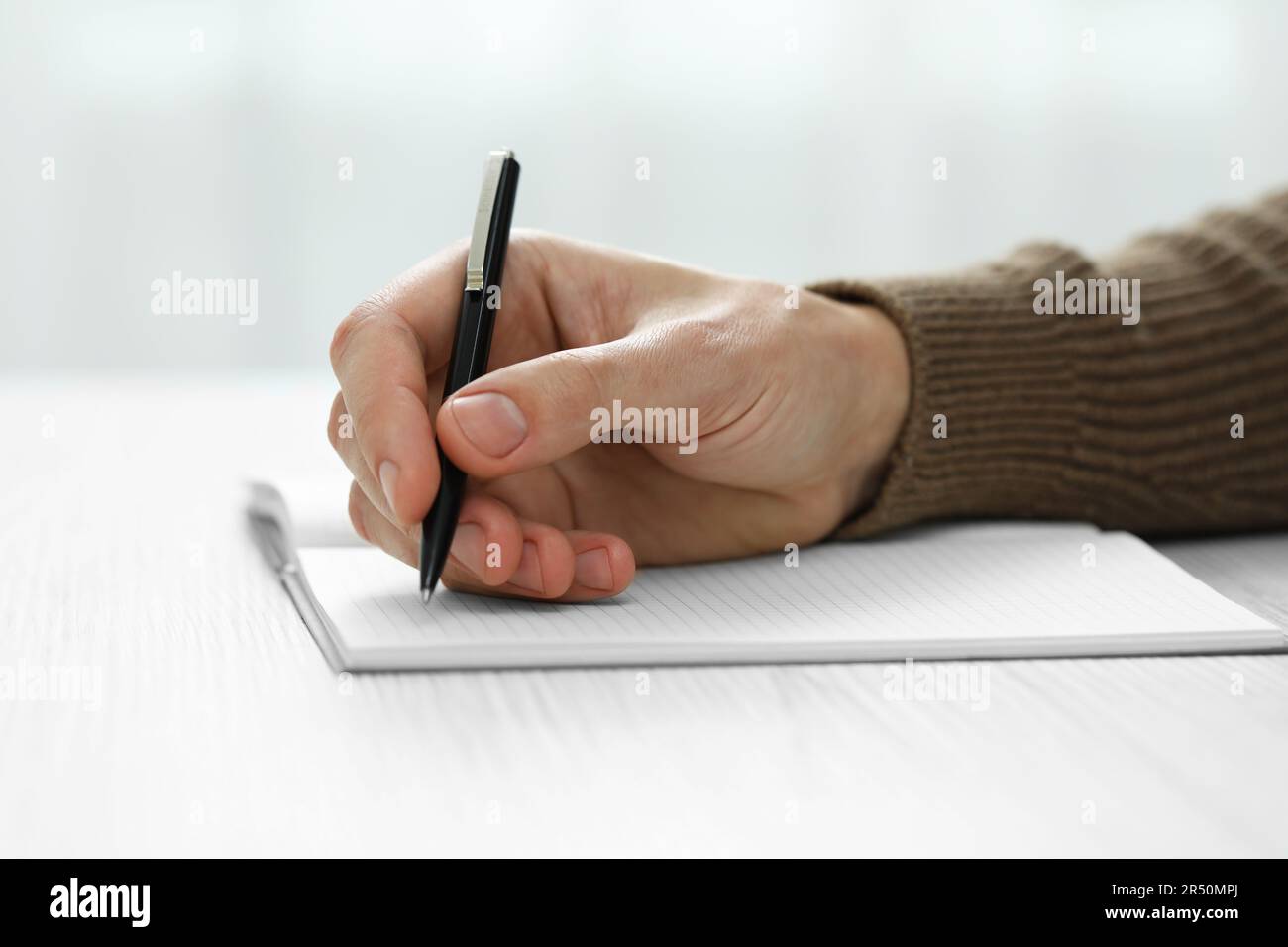 Man writing in notebook at white wooden table, closeup Stock Photo - Alamy