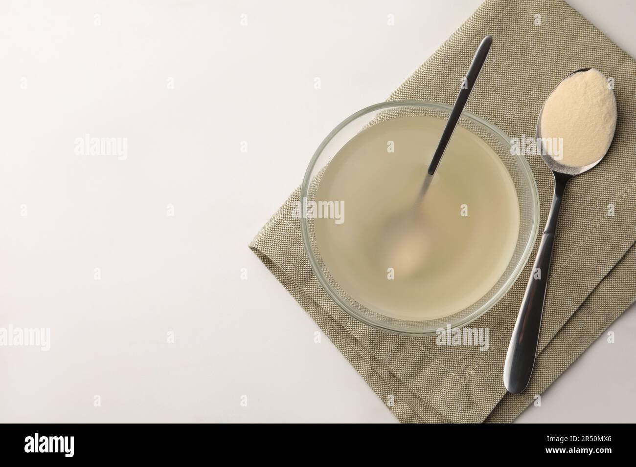Glass bowl of agar-agar jelly and spoon with powder on white marble ...