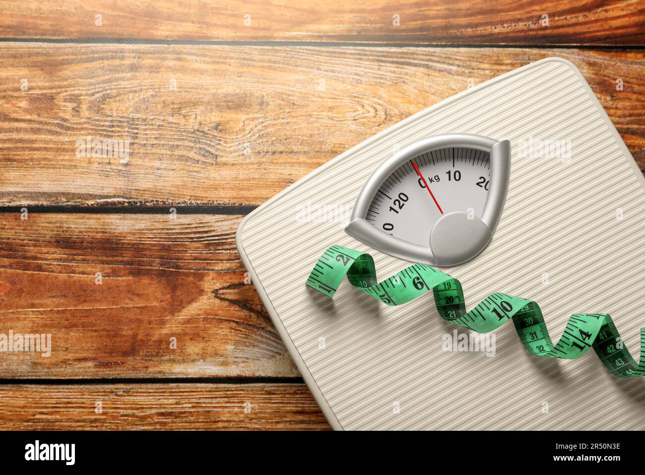 Weigh scales with measuring tape on wooden table, top view and space ...