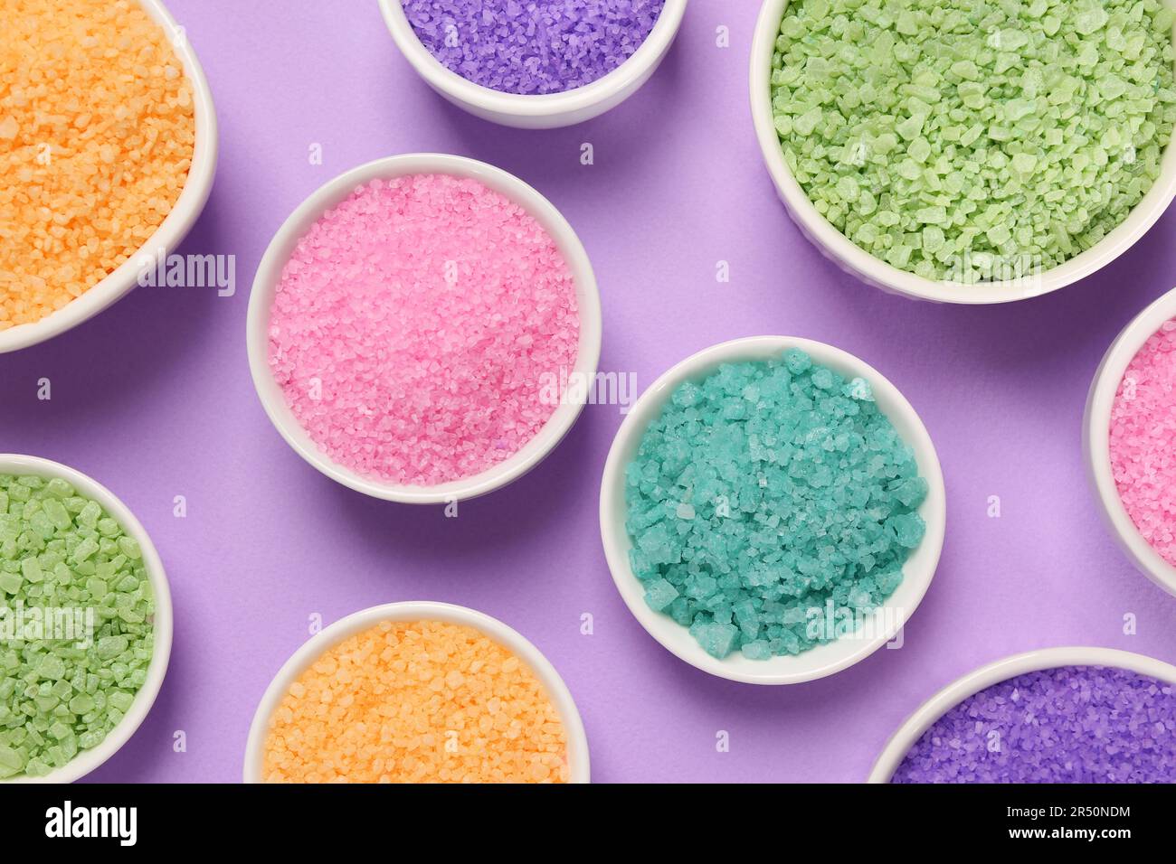 Different types of aromatic sea salt on purple background, flat lay ...