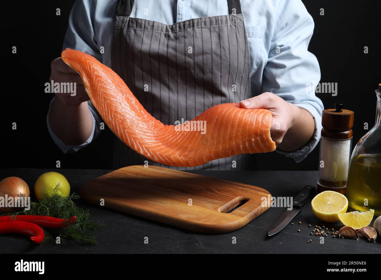 Man with raw salmon fillet at black table, closeup Stock Photo - Alamy