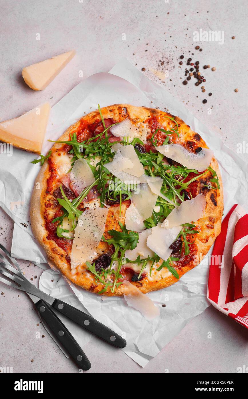 Pizza with mozzarella, ham, olives, rocket, and parmesan cheese Stock ...