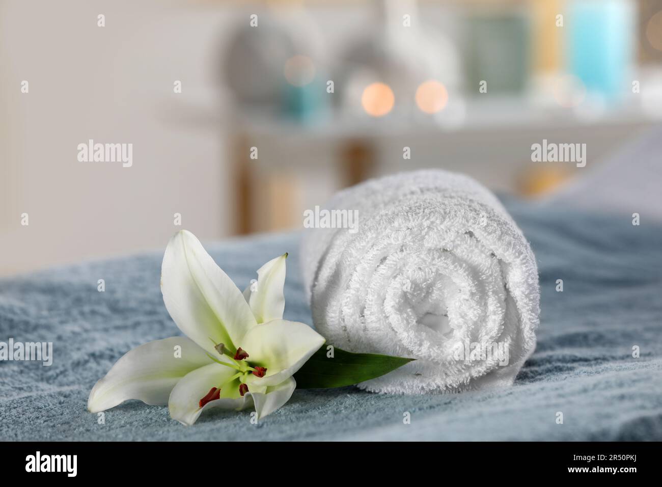 Spa composition with rolled towel and lily flower on massage table in wellness center Stock ...