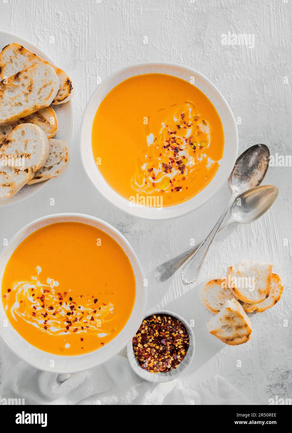 Creamy tomato soup with baguette and chilli flakes Stock Photo - Alamy