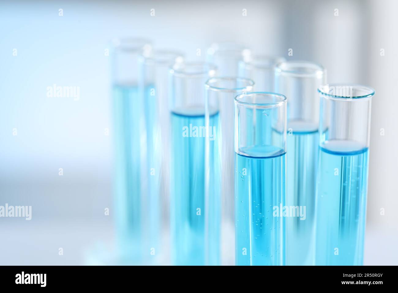 Test tubes with light blue liquid in laboratory, closeup. Space for ...