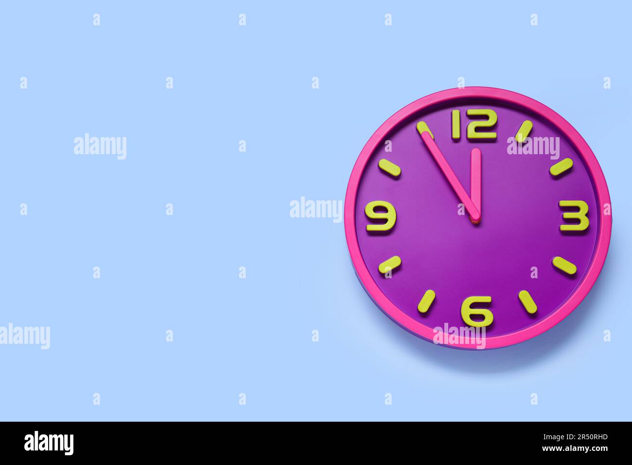 Clock showing five minutes until midnight on light blue background, top ...
