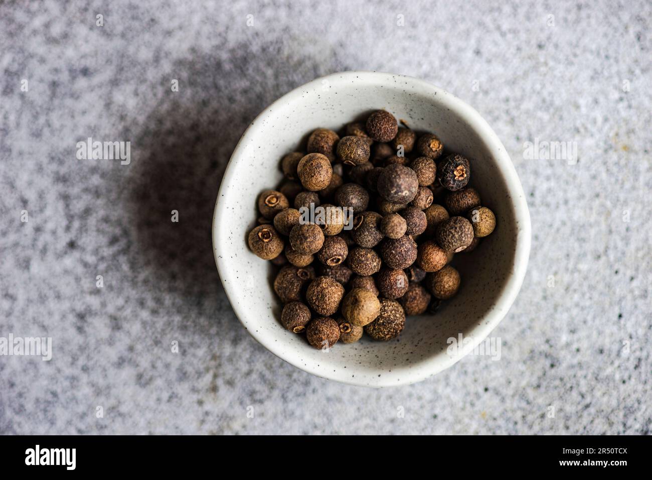 Stone bowl with black pepper spice on concrete background Stock Photo ...