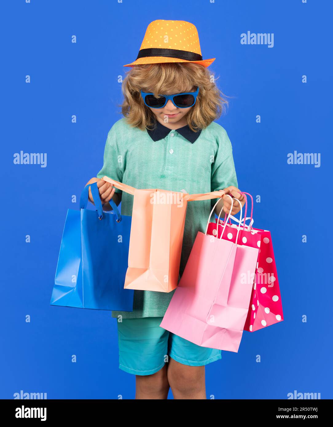 Kid boy in fashion clothes goes shopping. Kid with shopping packages ...