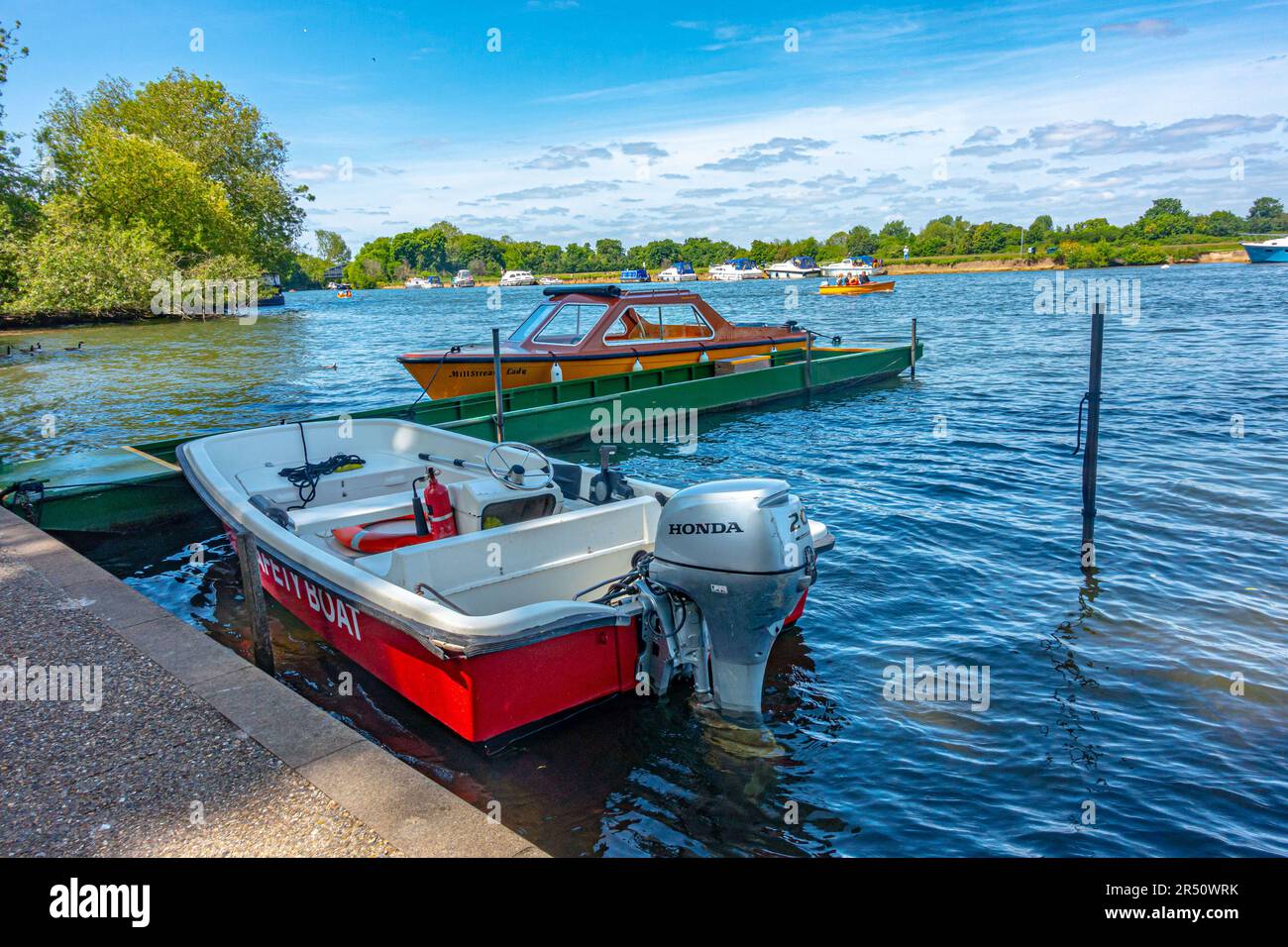 Boats including a safety boat moored on the banks of The River Thames ...