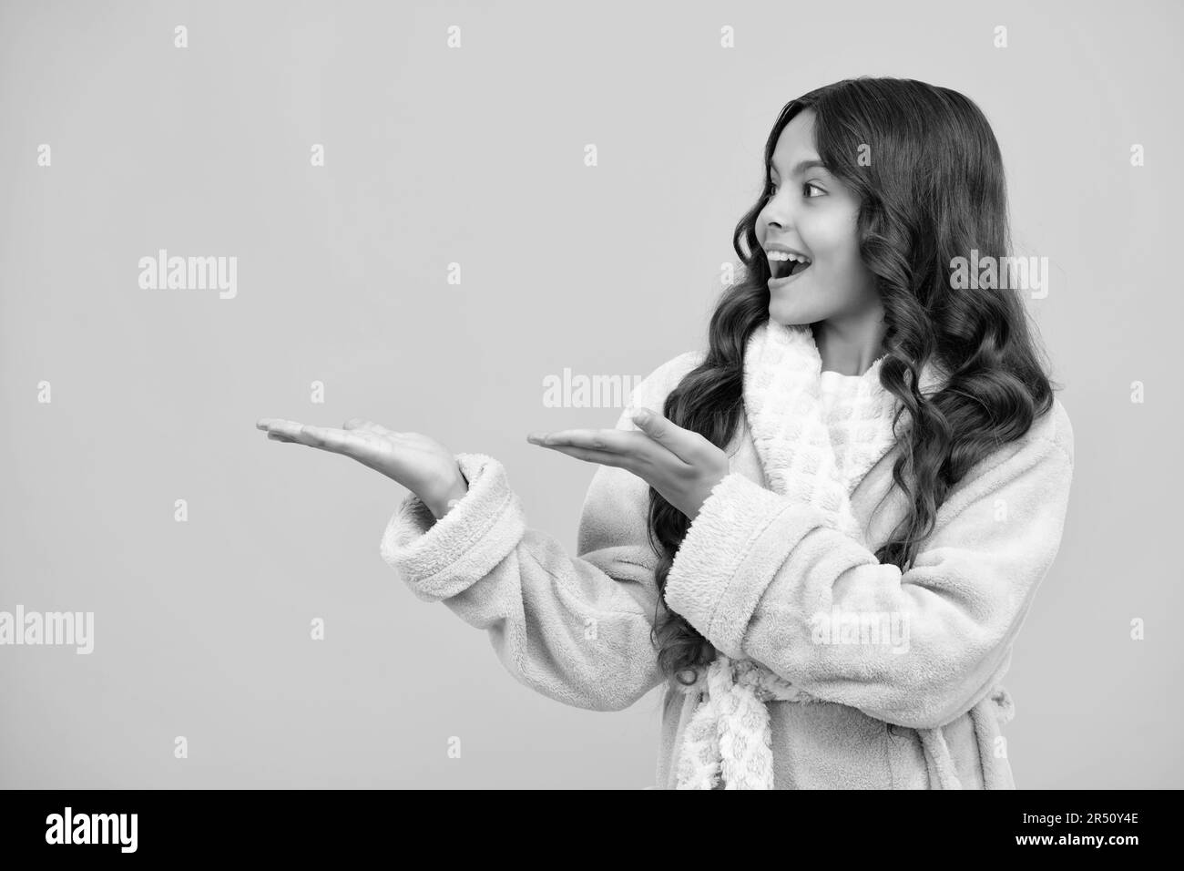 Positive teenager child points aside with cheerful expression, shows ...