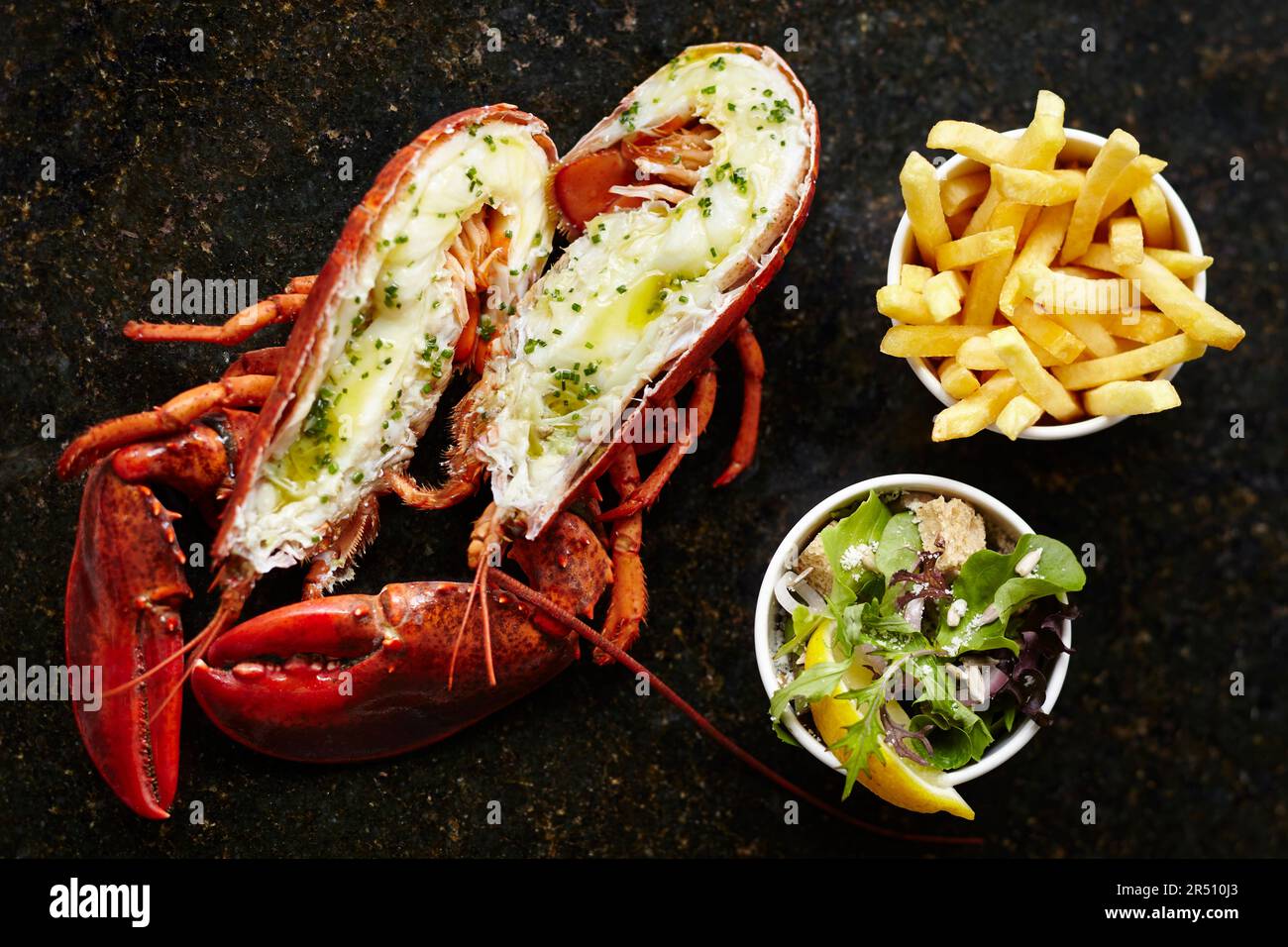 Cooked lobster split into two, in shell with garlic and herb butter ...