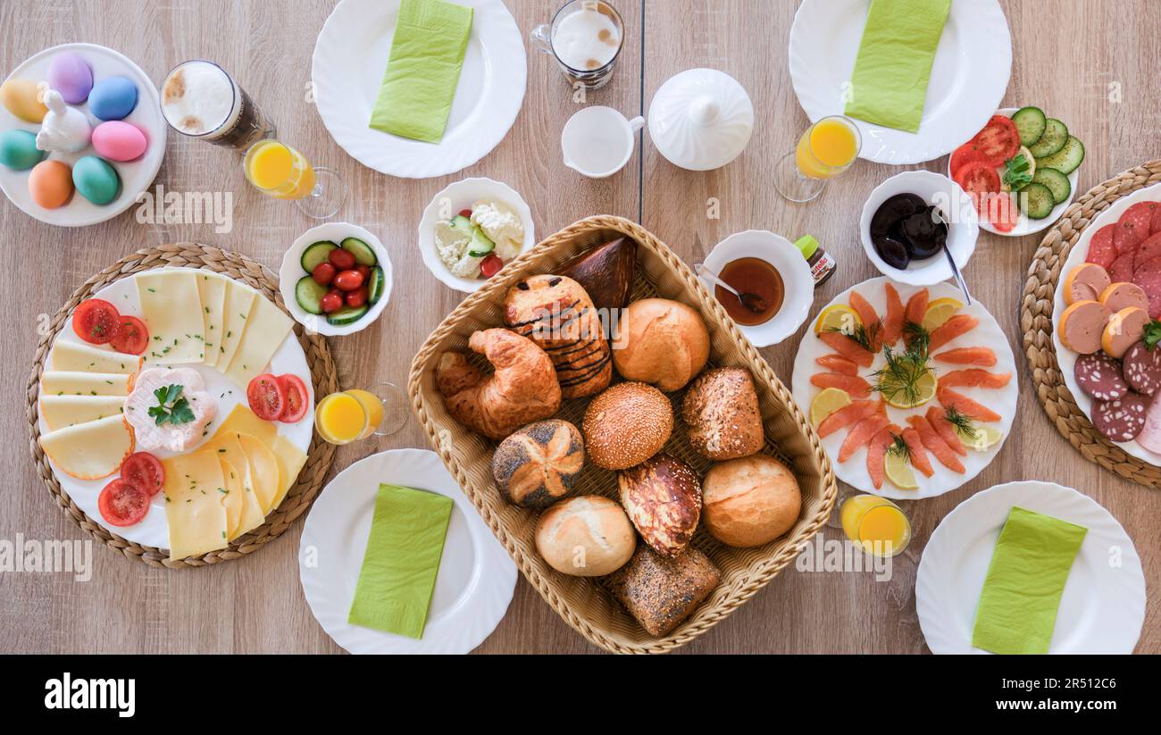 An Easter breakfast table laid with coloured eggs, rolls, salmon, and ...