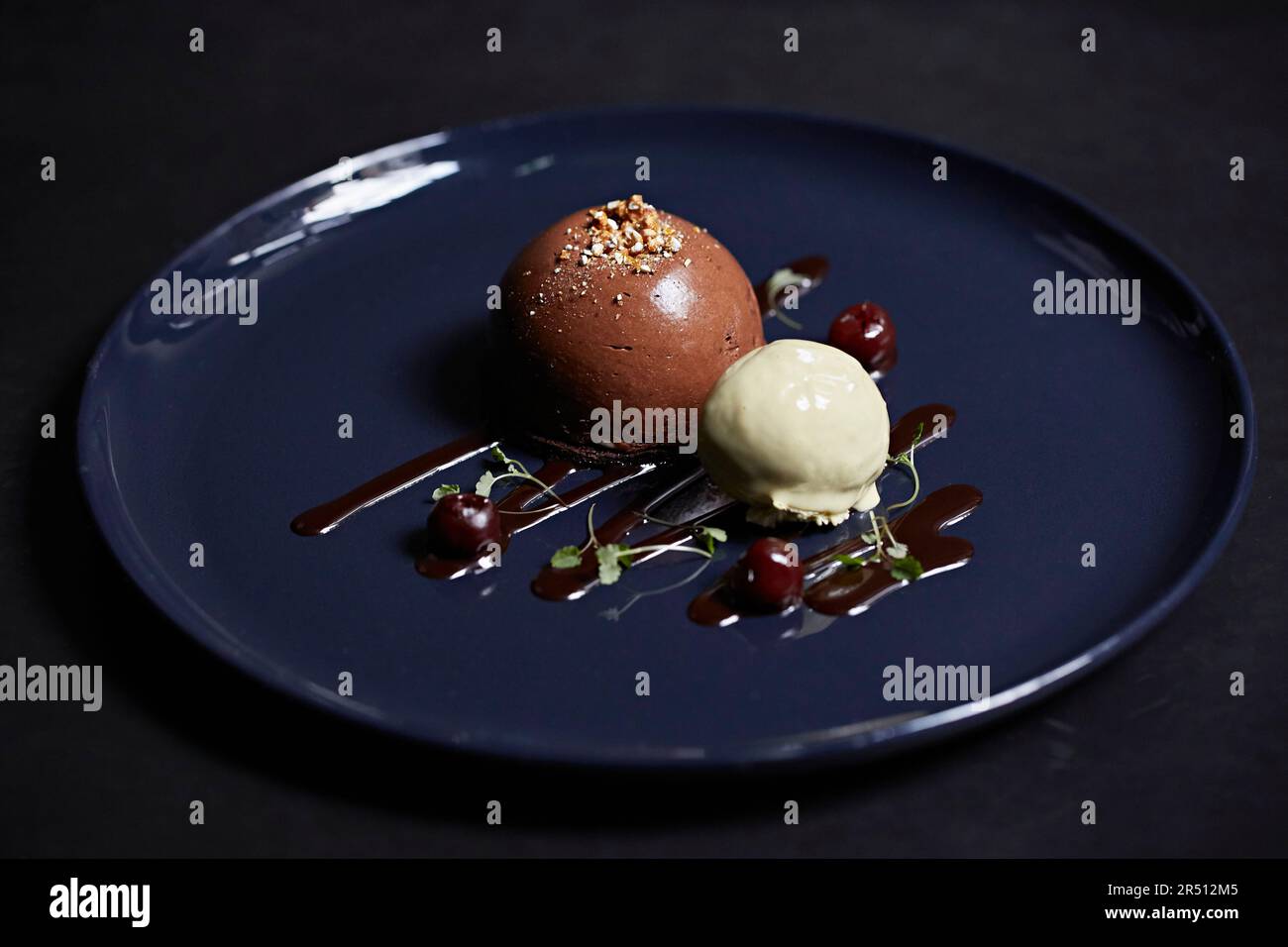 A mini dark chocolate dome served with cherries and ice cream Stock ...
