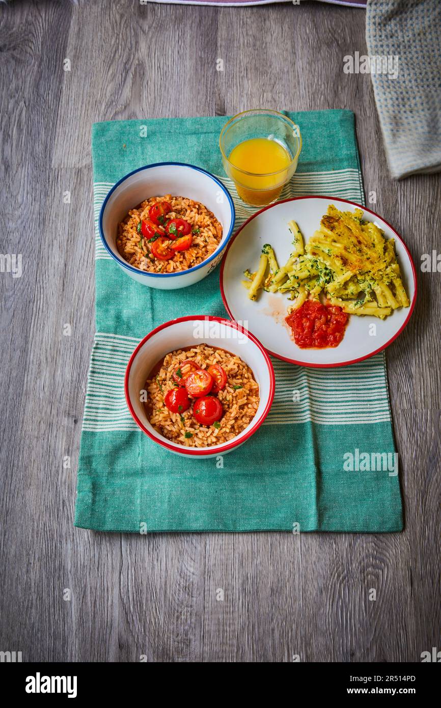 Two bowls of seasoned rice with tomatoes and a serving of macaroni ...