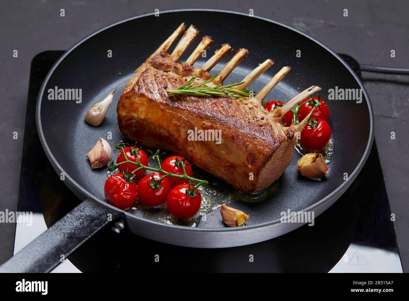 Pan fried rack of lamb with cherry tomatoes and garlic Stock Photo - Alamy