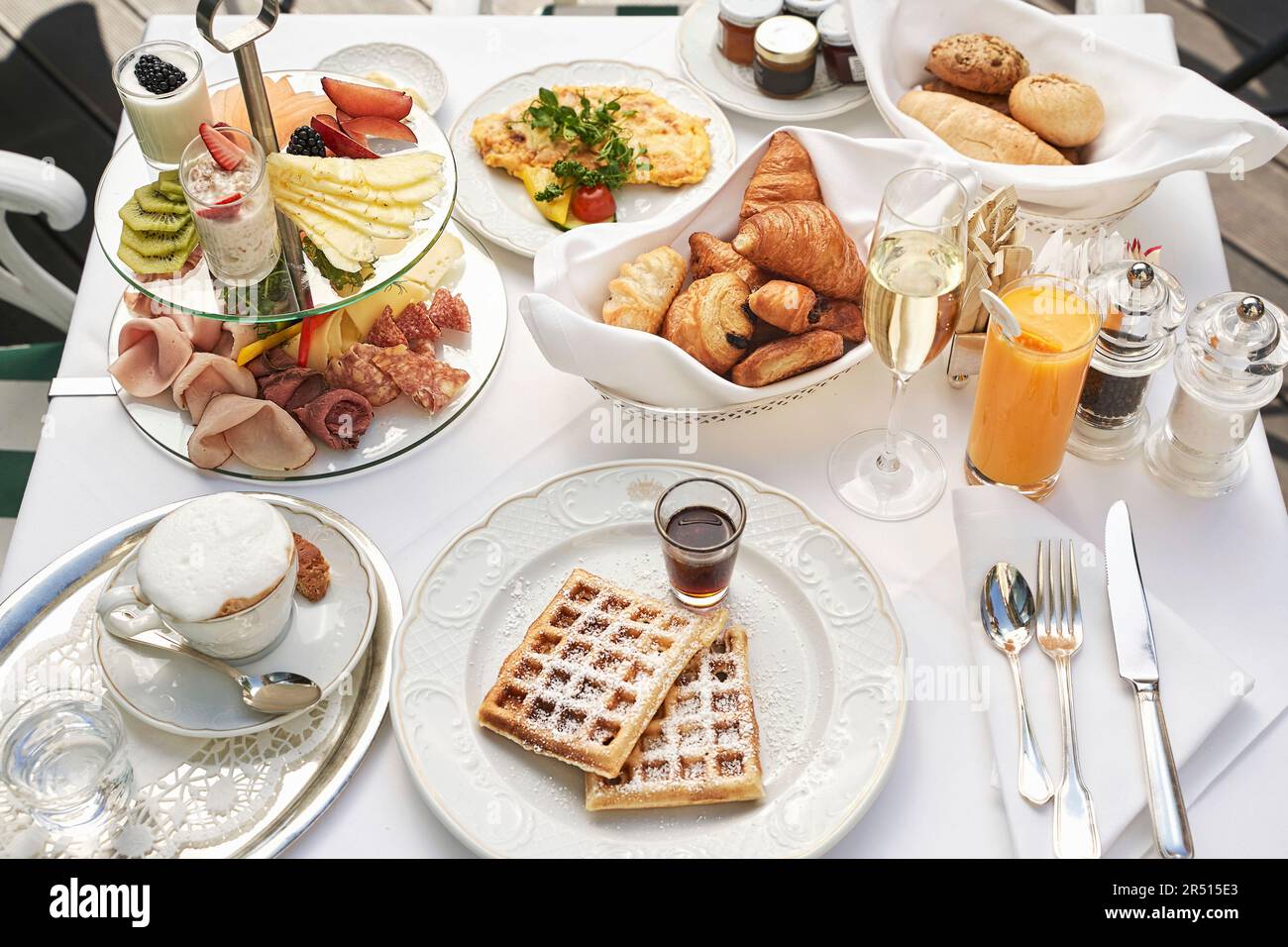 Breakfast table with scrambled eggs, croissants, pastries, waffles ...