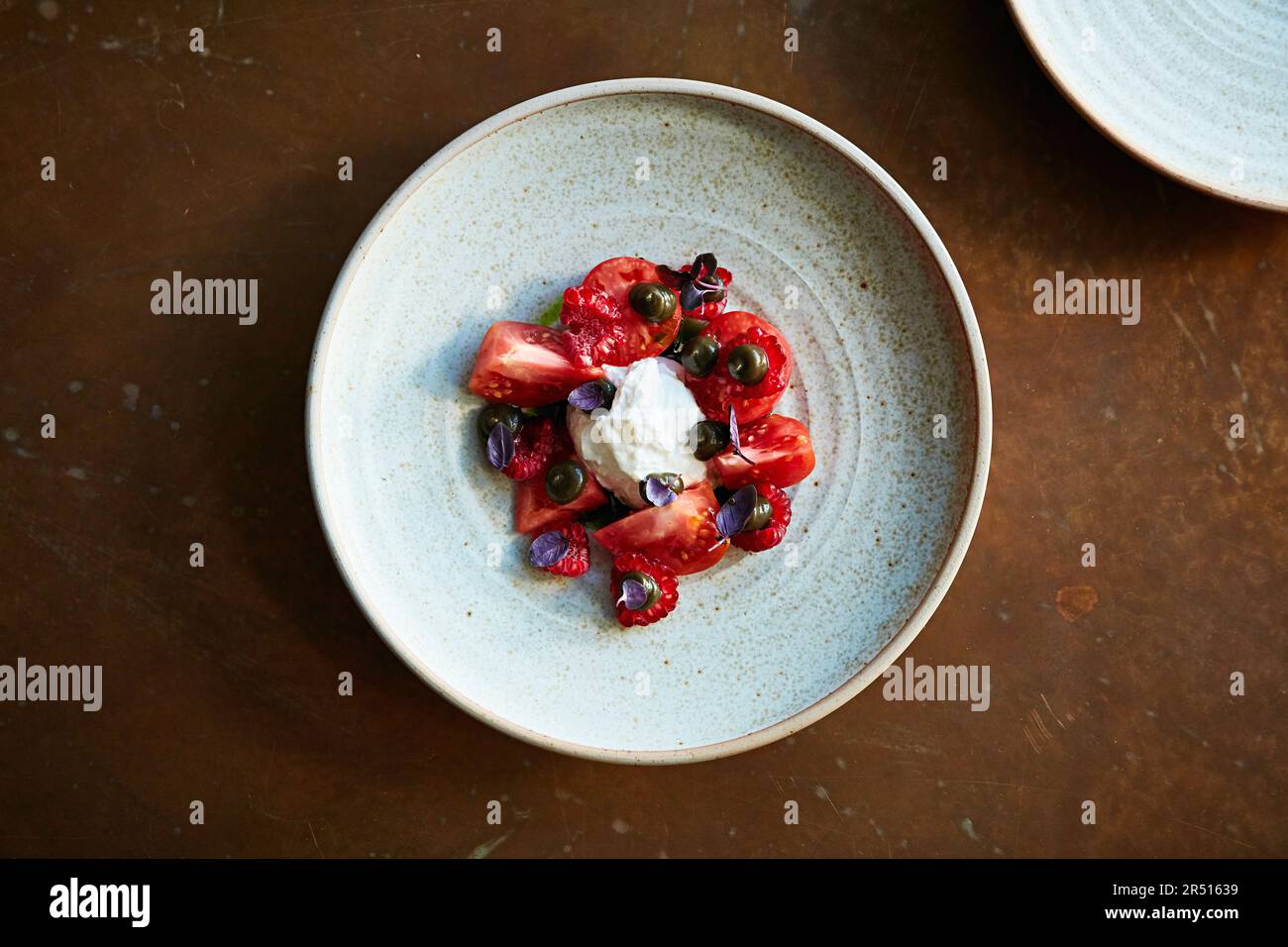 Tomato salad with burrata, raspberries and capers Stock Photo - Alamy